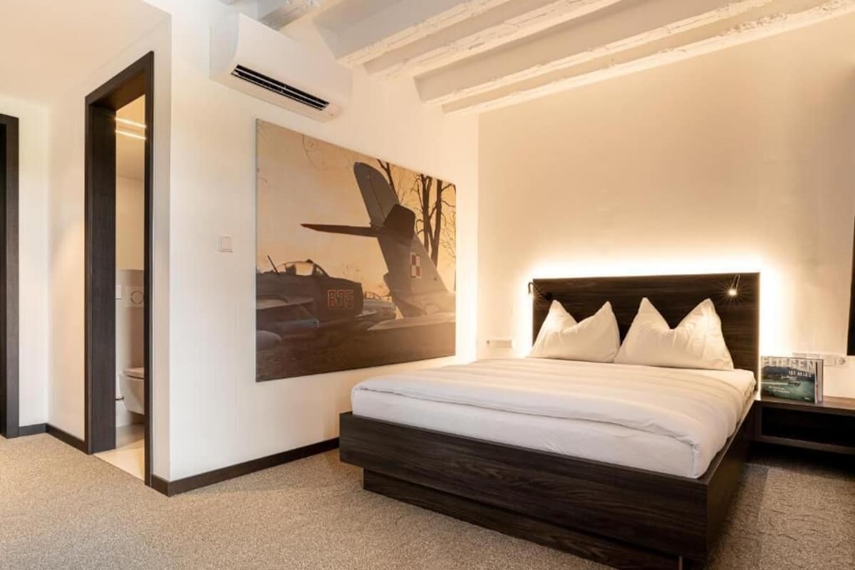 Quarto com cama grande, pintura na parede e mesa de cabeceira.