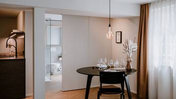 Uma sala de jantar moderna com uma mesa redonda, cadeiras pretas e um lustre.