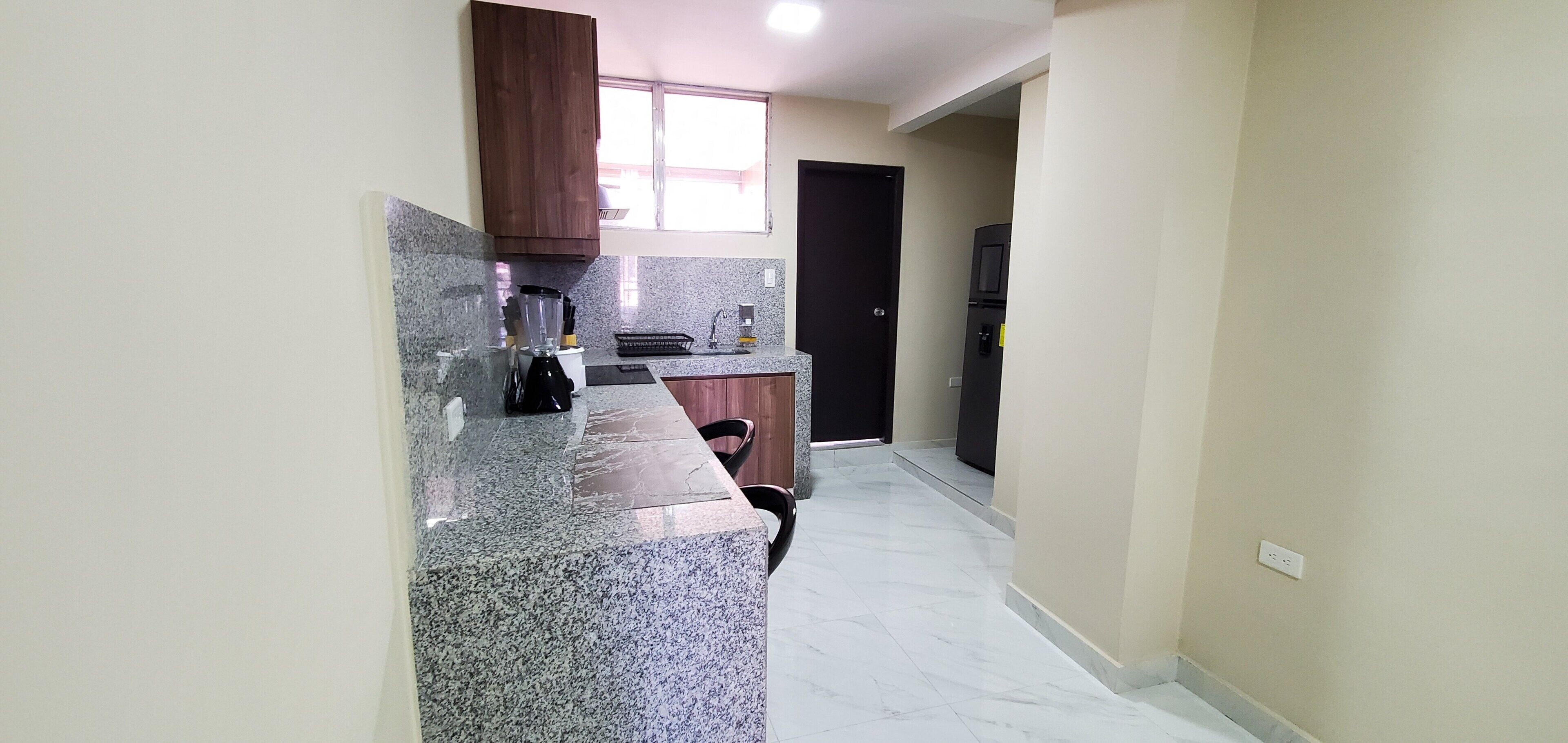 Cozinha com bancadas de granito, uma cafeteira preta e uma geladeira preta.