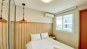 Quarto de hotel com uma cama, janela, ar condicionado e luminária pendente.