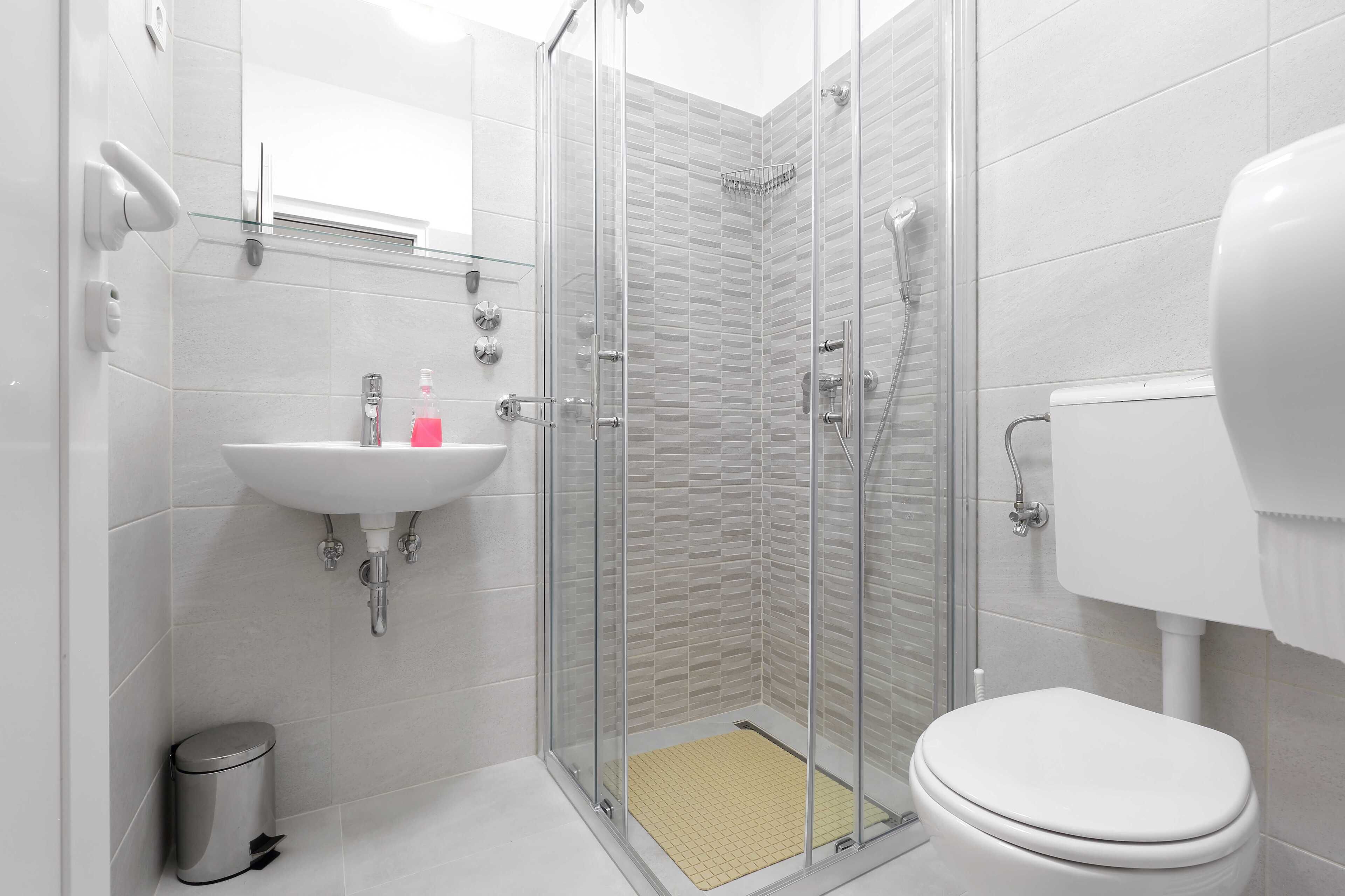 Casa de banho moderna com cabine de duche em vidro, lavatório branco e sanita.