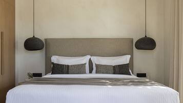 Quarto moderno com cama grande, duas luminárias pendentes, um banco de madeira e um ventilador de teto.