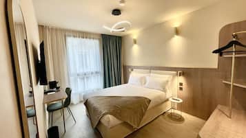 Quarto de hotel moderno com cama grande, mesa de cabeceira e espelho.