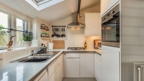 Cozinha moderna com claraboia, eletrodomésticos de aço inoxidável e armários brancos.