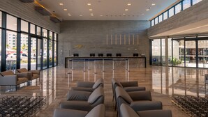 Um hall amplo com balcão de recepção, área de estar e grandes janelas com vista para o exterior.