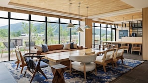 Uma sala de estar ampla, com uma grande mesa de madeira, assentos confortáveis e janelas espaçosas com vista para o exterior.