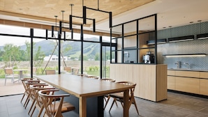 Uma cozinha moderna com uma ilha grande, cadeiras de madeira e vista para o exterior.