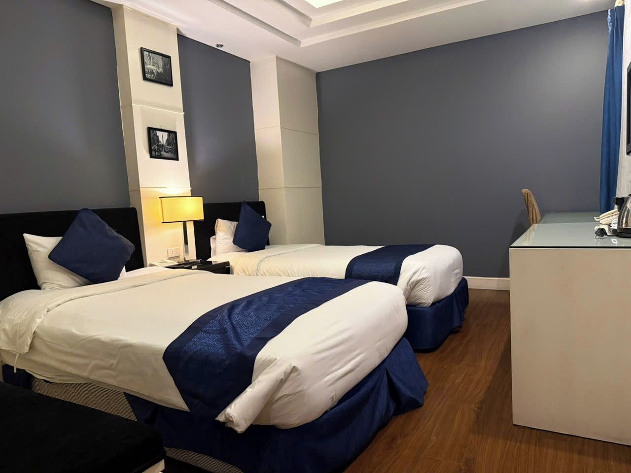 Quarto de hotel com duas camas, uma escrivaninha e uma cadeira.