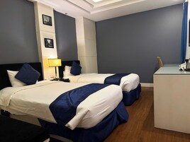 Quarto de hotel com duas camas, uma escrivaninha e uma cadeira.