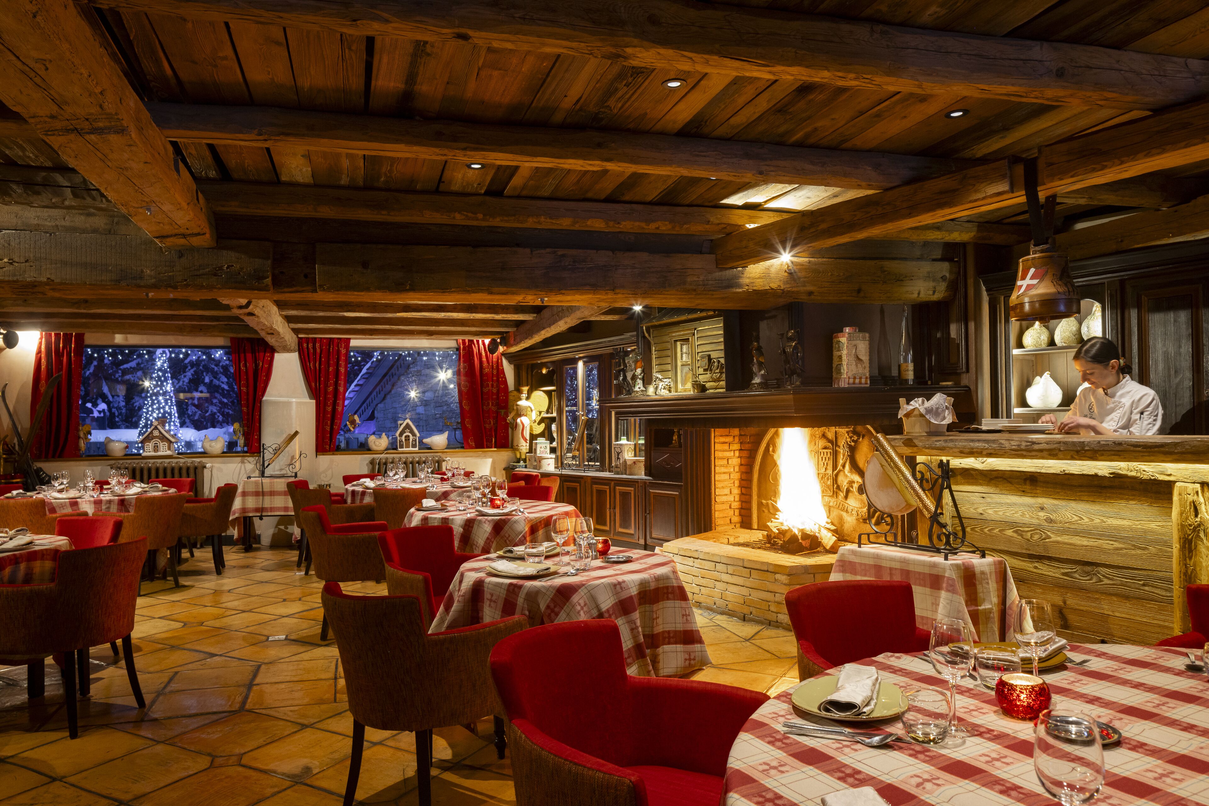 Um restaurante acolhedor com vigas de madeira, cadeiras vermelhas e mesas preparadas para refeições.