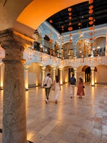 Um interior espaçoso com teto alto, colunas em arco e uma escadaria central.