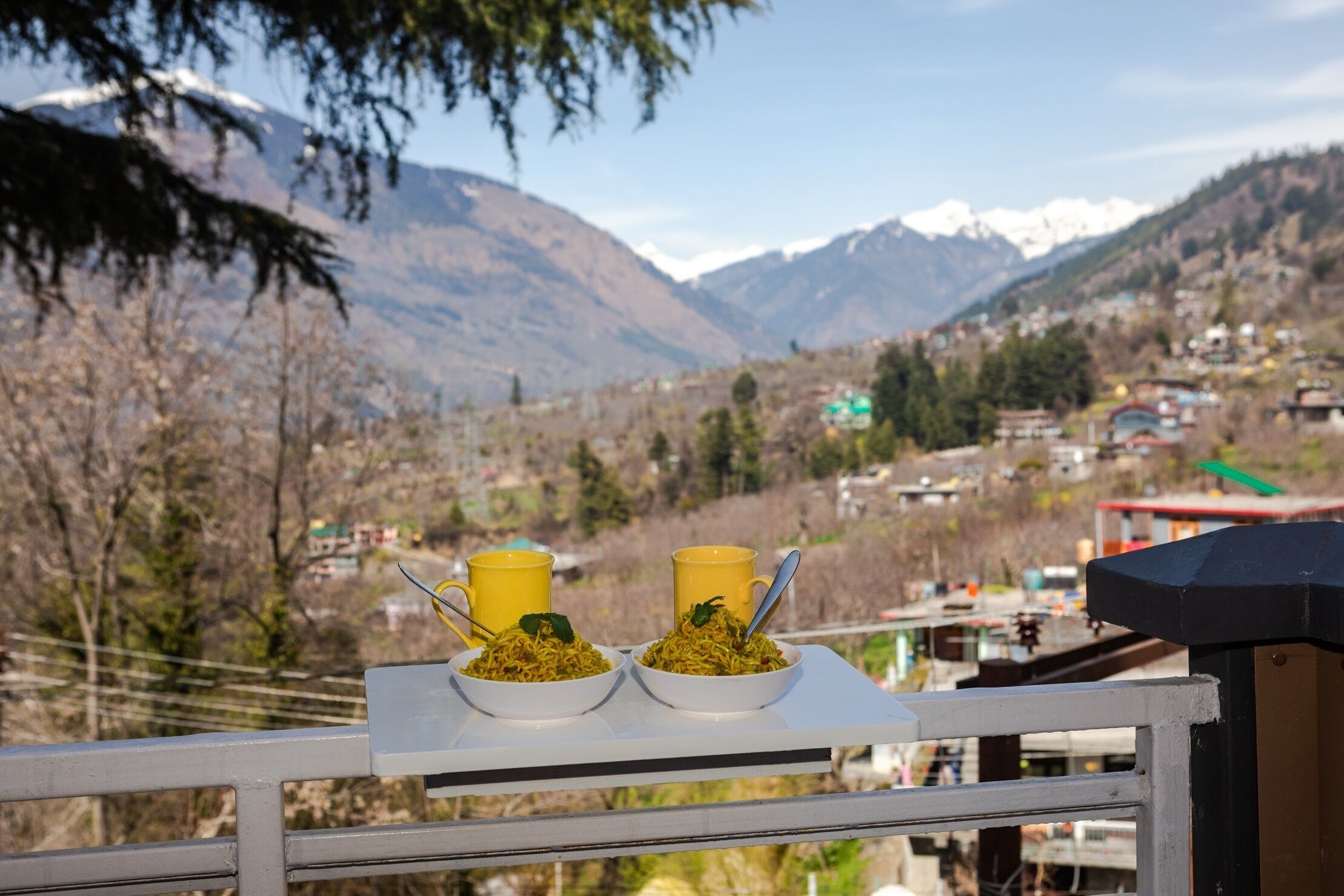Varanda com duas tigelas de comida e vista para uma paisagem montanhosa.