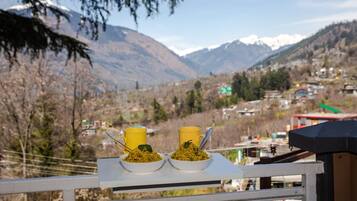 Varanda com duas tigelas de comida e vista para uma paisagem montanhosa.