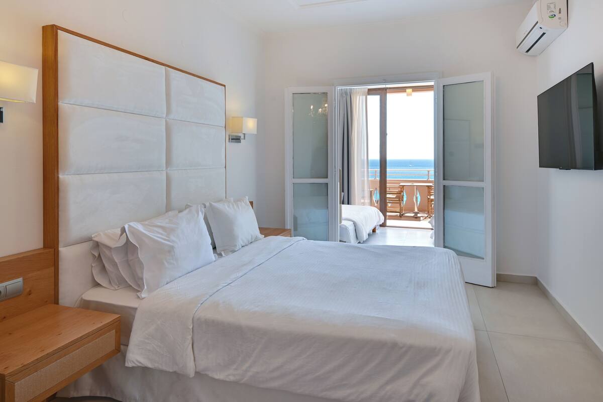 Quarto de hotel com cama, mesa de cabeceira e televisão.