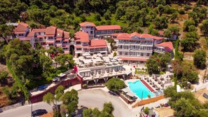 Vista aérea de um resort com vários edifícios, piscina e áreas de estar ao ar livre.