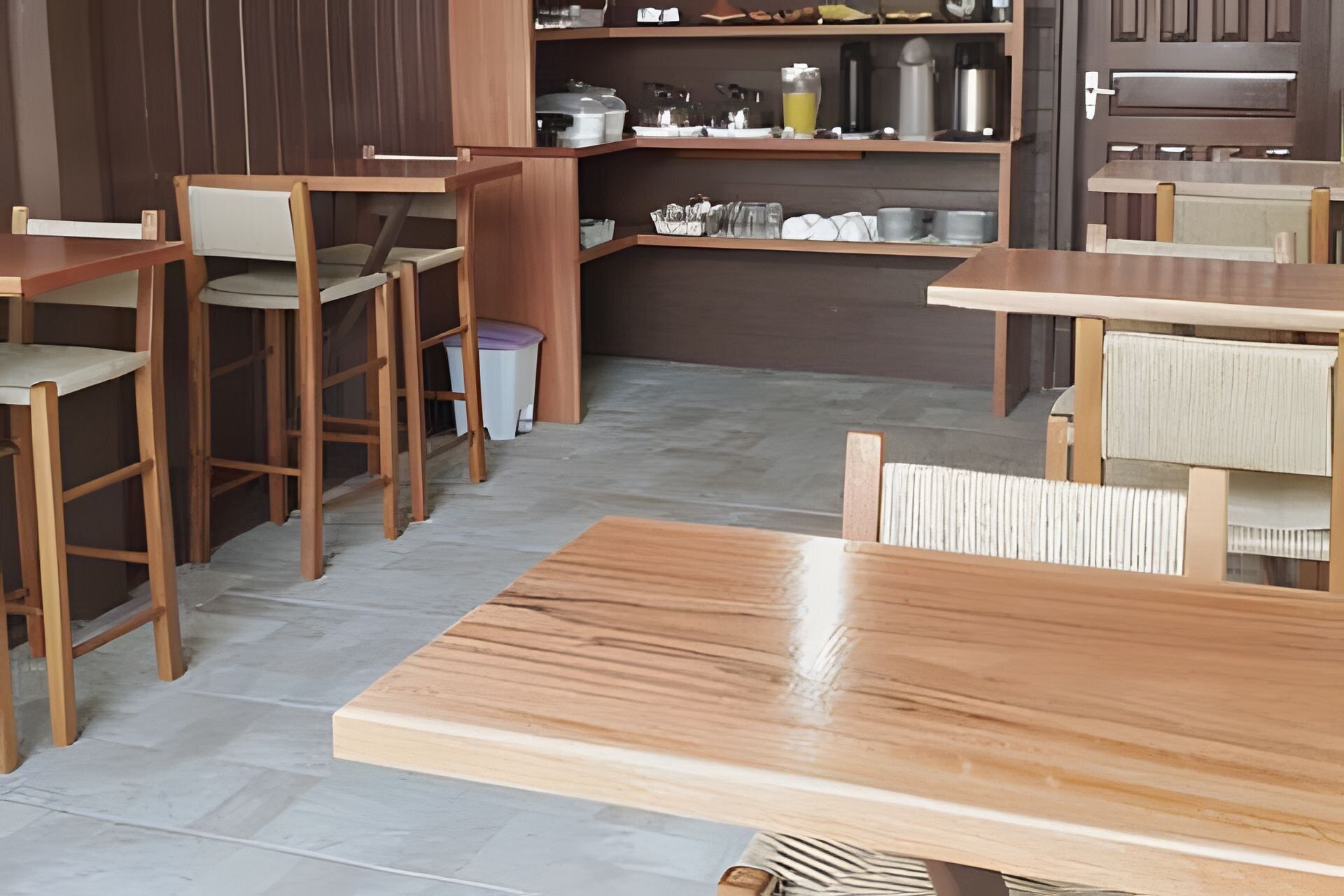Cozinha moderna com mobiliário de madeira, incluindo uma mesa central e cadeiras, e prateleiras embutidas com utensílios de cozinha.