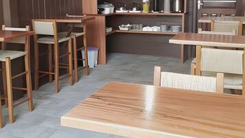 Cozinha moderna com mobiliário de madeira, incluindo uma mesa central e cadeiras, e prateleiras embutidas com utensílios de cozinha.