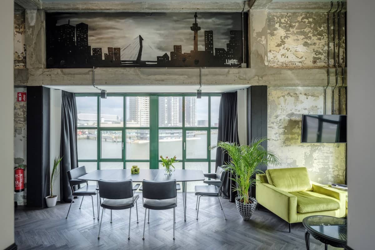 Um interior moderno com área de jantar, sofá e uma janela grande com vista para a cidade.