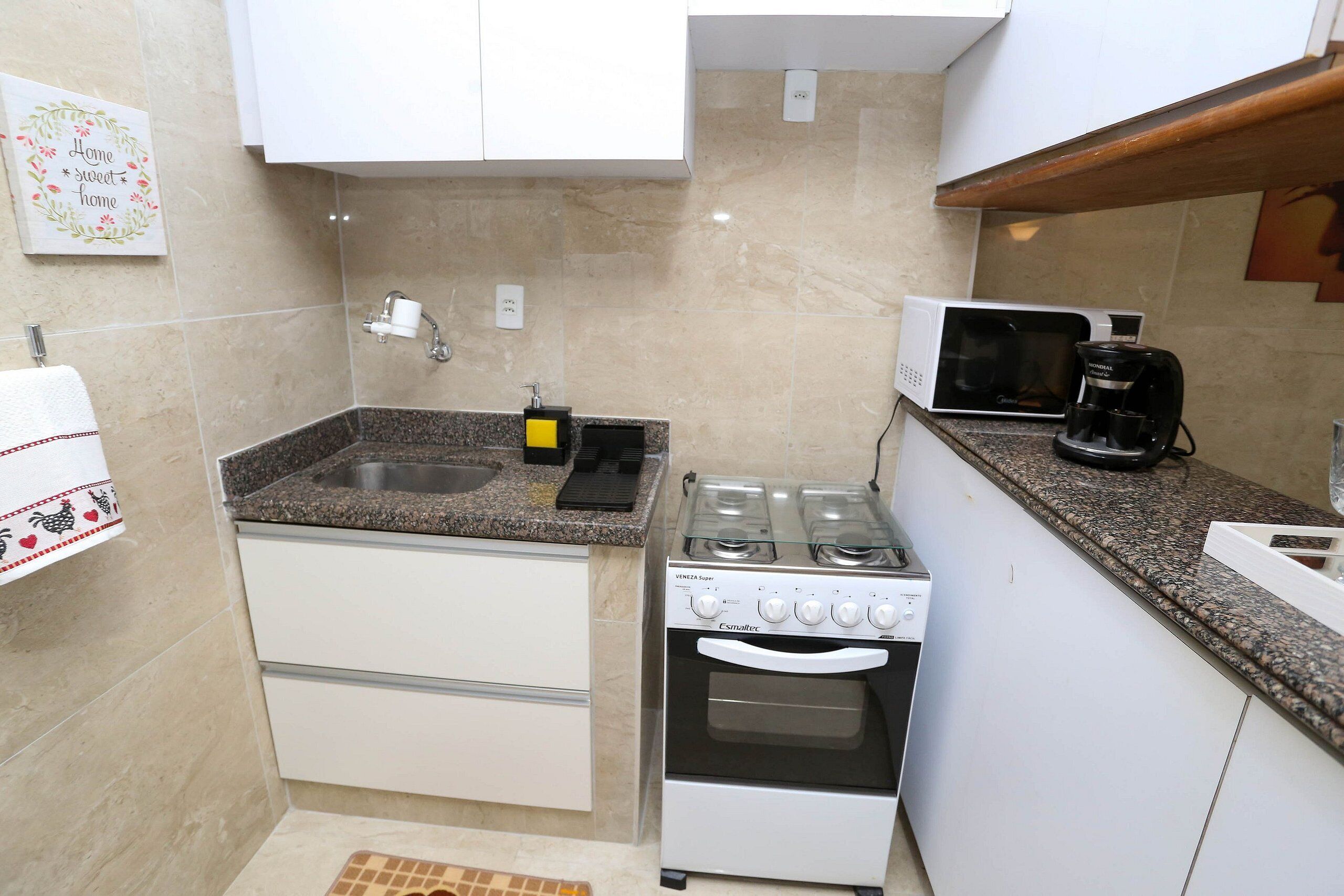 Uma cozinha compacta com fogão a gás, micro-ondas e pia.