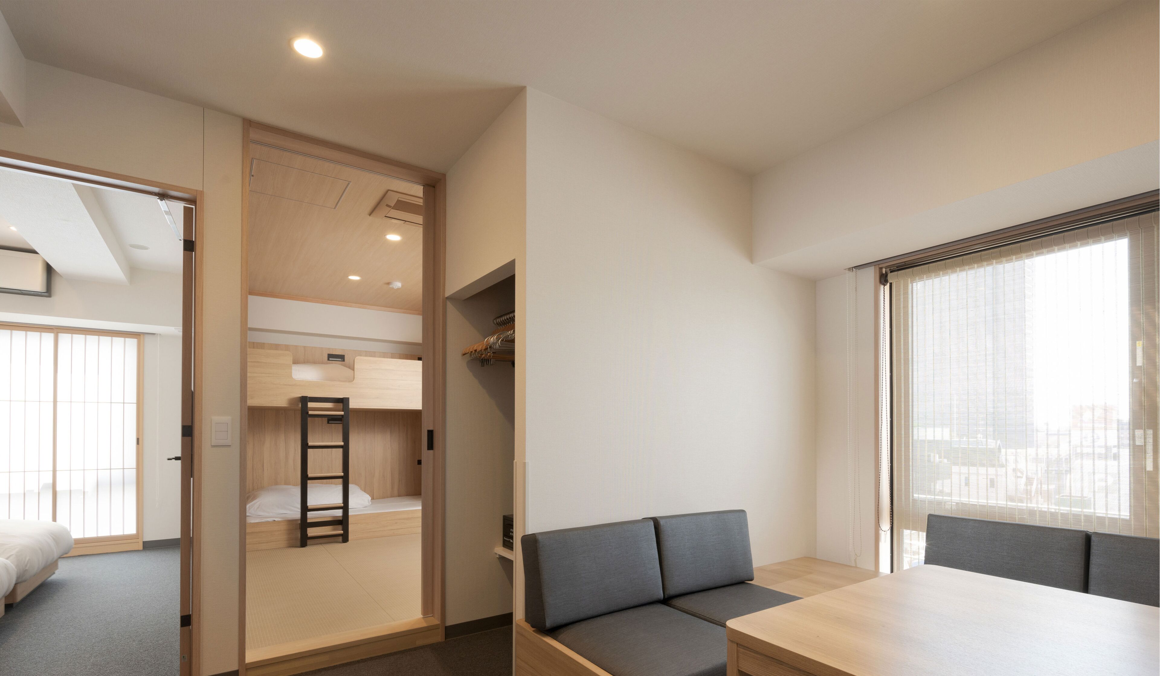 Quarto compacto com uma cama beliche, uma mesa pequena e um sofá.