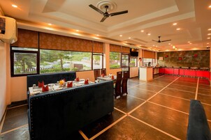 Um restaurante com um balcão comprido, várias mesas e vista para o exterior.