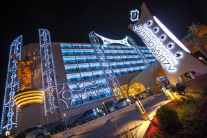 Um hotel com fachada moderna, várias varandas e iluminação decorativa.
