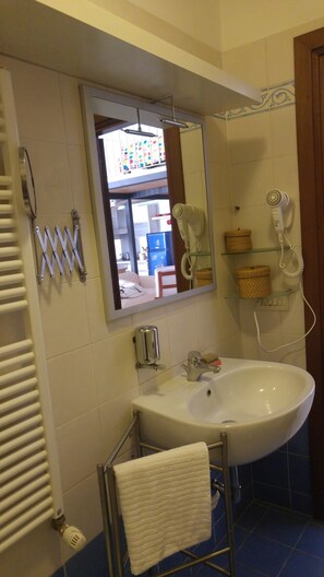 Casa de banho com lavatório branco, espelho, porta-toalhas, secador de cabelo e telefone.