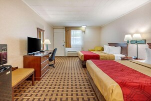 Quarto de hotel com cama, secretária com computador, televisão e janela com cortinas.