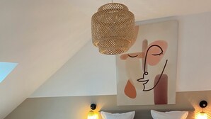 Quarto com uma cama grande, duas luminárias de cabeceira, uma cadeira e um lustre.