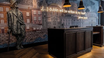 Espaço de bar com um mural da arquitetura de Dublin, uma estátua e uma citação de James Joyce.