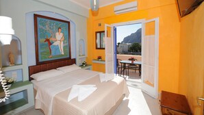 Quarto de hotel com cama, um quadro, varanda e vista para as montanhas.