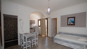 Uma sala ampla com uma mesa de jantar, sofá e cozinha ao fundo.