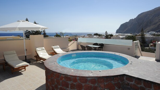 Terraço no telhado com banheira de hidromassagem, espreguiçadeiras e uma mesa.