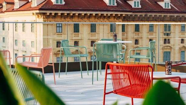 Terraço com área de estar ao ar livre e vista para um edifício histórico com cúpulas.