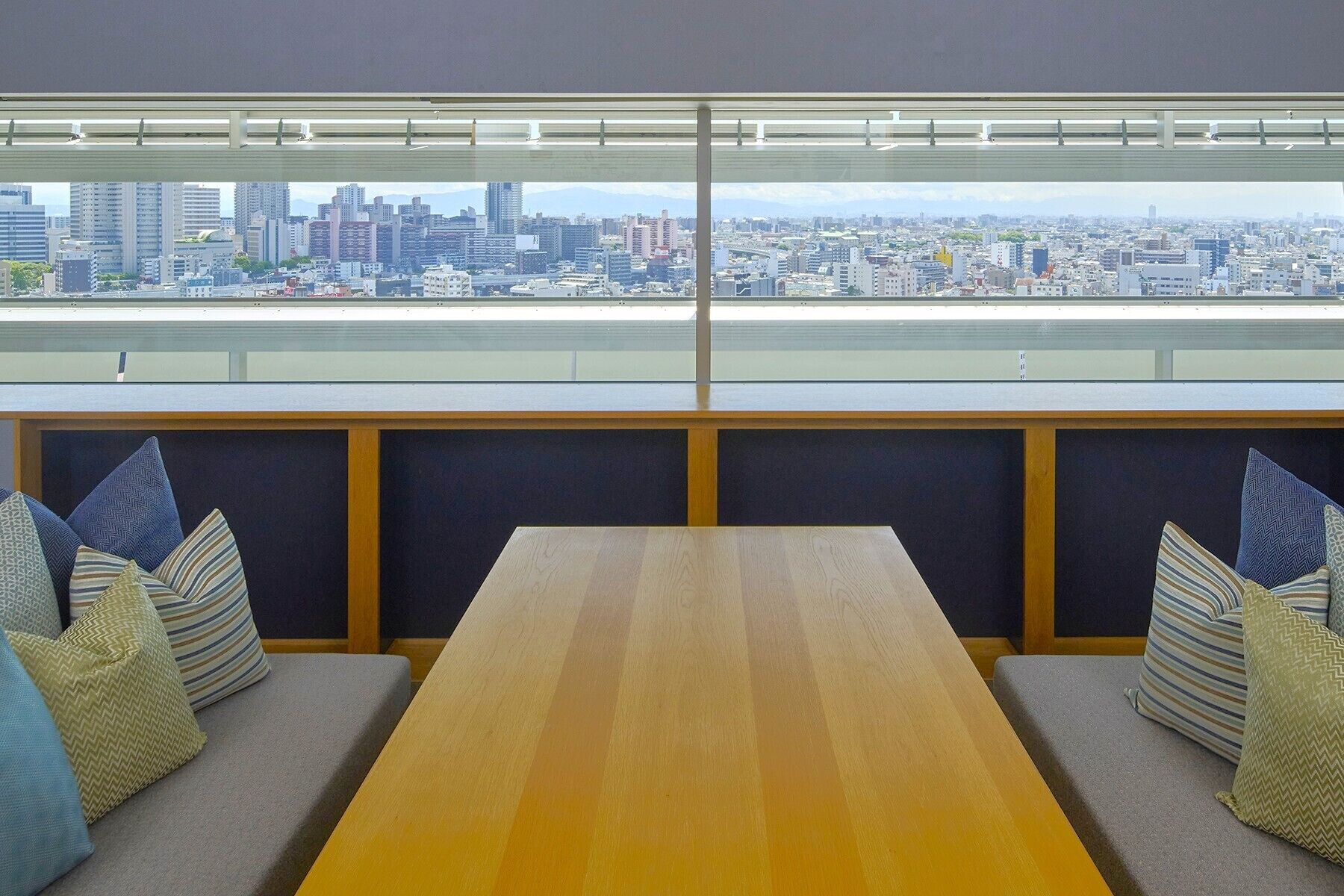 Uma sala de conferências com vista para a cidade, uma mesa comprida e assentos acolchoados.
