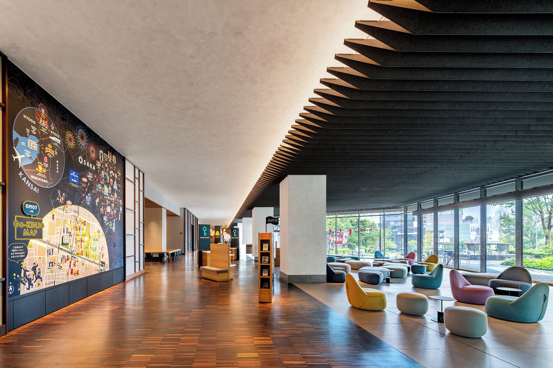 Um hall amplo com piso de madeira, um mural de mapa vibrante e uma área de estar com cadeiras modernas.