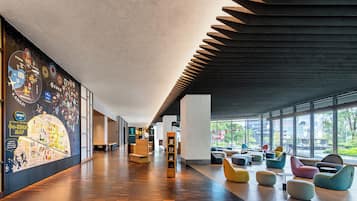 Um hall amplo com piso de madeira, um mural de mapa vibrante e uma área de estar com cadeiras modernas.