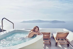 Uma pessoa relaxando em uma banheira de hidromassagem com vista para ilhas ao longe.