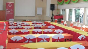 Uma sala de conferências com fileiras de mesas e cadeiras, um quadro branco e um projetor.