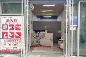 Uma área de recepção com balcão de mármore, portas de vidro e um cartaz na parede.