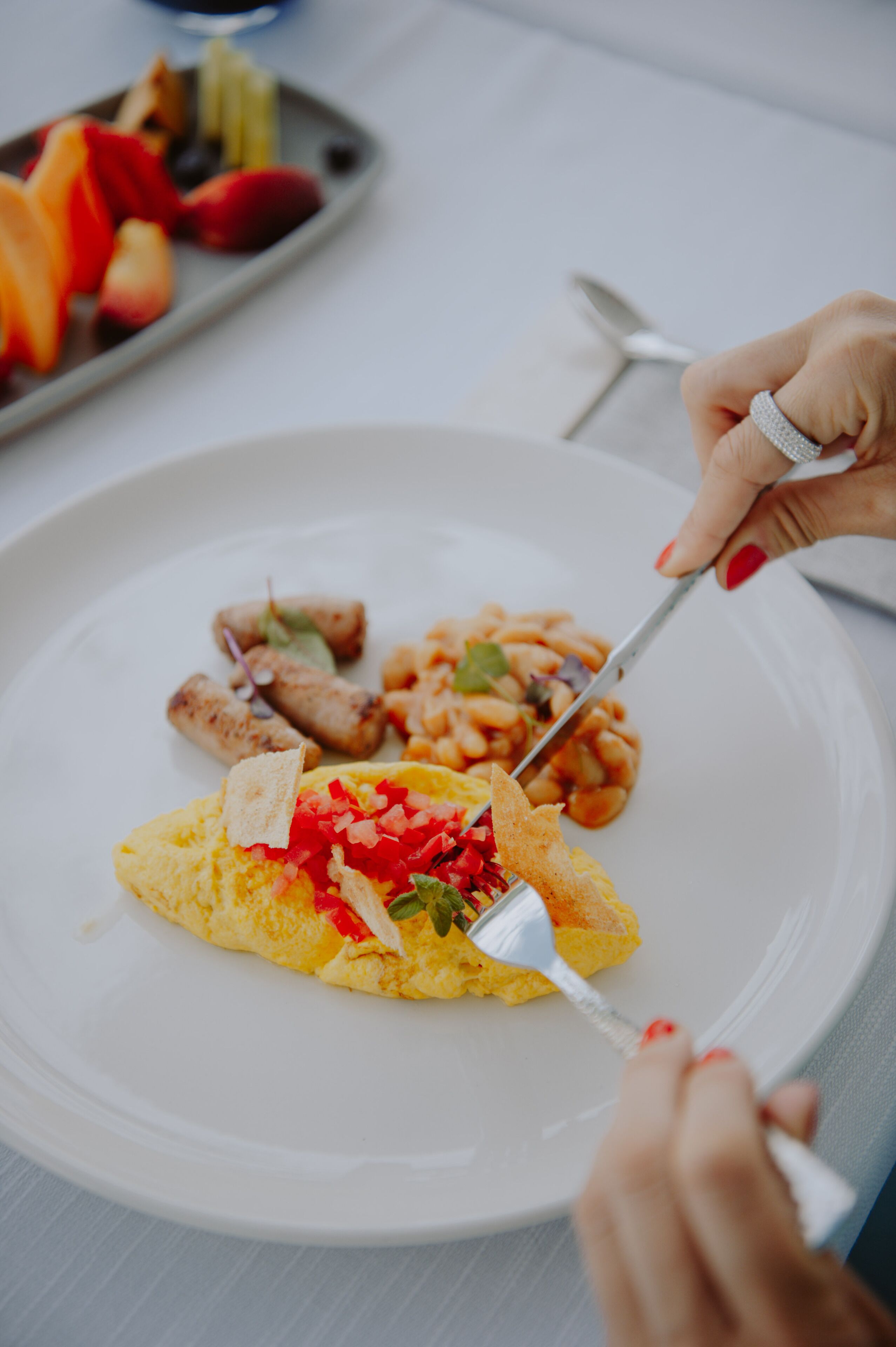 Um prato com omelete, salsichas e feijão como acompanhamento.