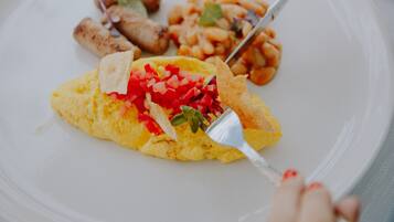 Um prato com omelete, salsichas e feijão como acompanhamento.