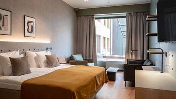 Quarto de hotel moderno com uma cama grande, uma escrivaninha e vista para a cidade.