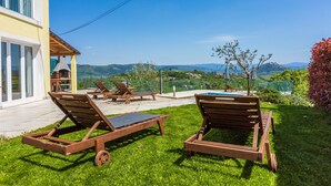 Área da piscina com espreguiçadeiras de madeira e vista para uma cordilheira.