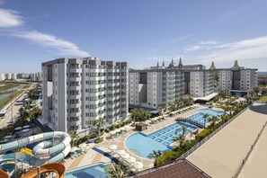 Um hotel moderno com vários andares, piscina e escorrega aquático.