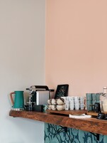Um espaço para café com uma máquina de café, uma chaleira verde e pilhas de copos brancos e verdes.