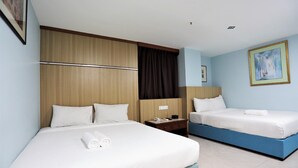 Quarto de hotel com duas camas, cabeceira de madeira, mesa de cabeceira e um quadro na parede.