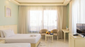 Quarto de hotel com duas camas, uma escrivaninha, uma cadeira, uma televisão e uma janela com cortinas.