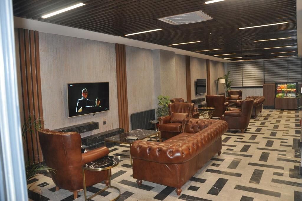 Um hall moderno com sofás de couro, televisão de tela plana e piso estampado.