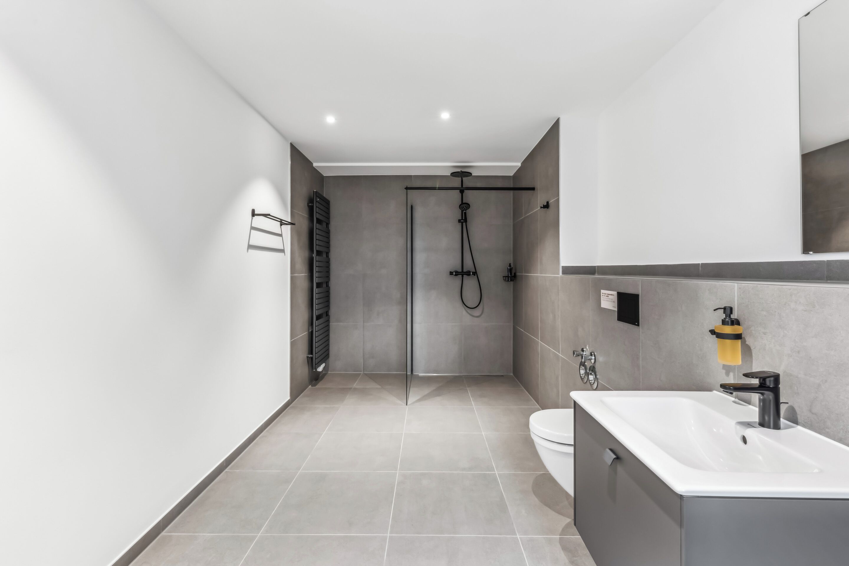 Uma casa de banho moderna com chuveiro, sanita e lavatório.